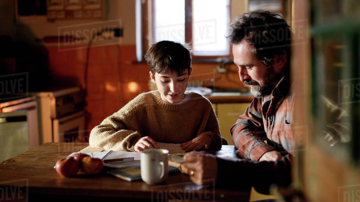 A poor mature father and small daughter learning indoors at home ...