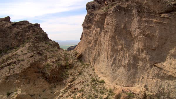 Flying through a notch in sandstone cliffs to reveal a wide valley ...