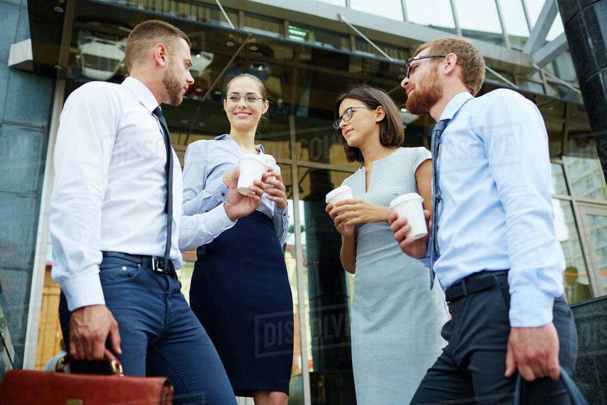 Four colleagues talking outdoors after work - Stock Photo - Dissolve