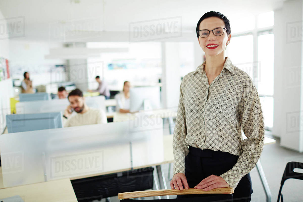 Successful employer looking at camera on background of working managers ...