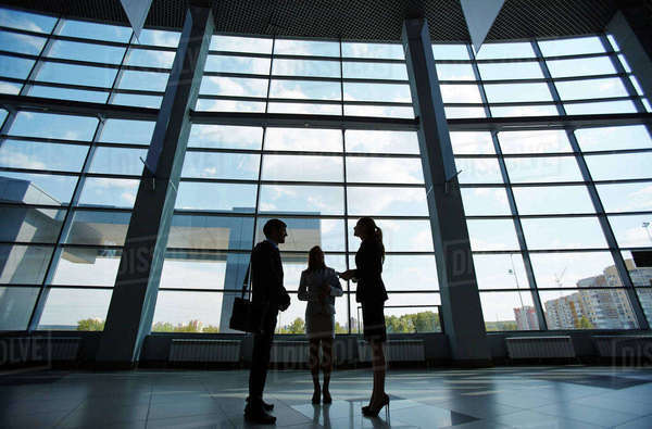 Three people standing in business center and talking - Stock Photo ...