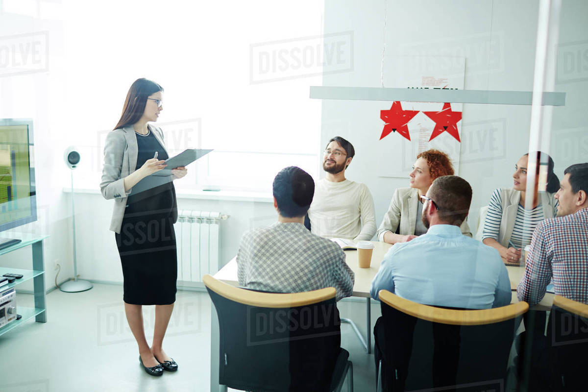 Confident colleagues listening to young employee reporting about new ...