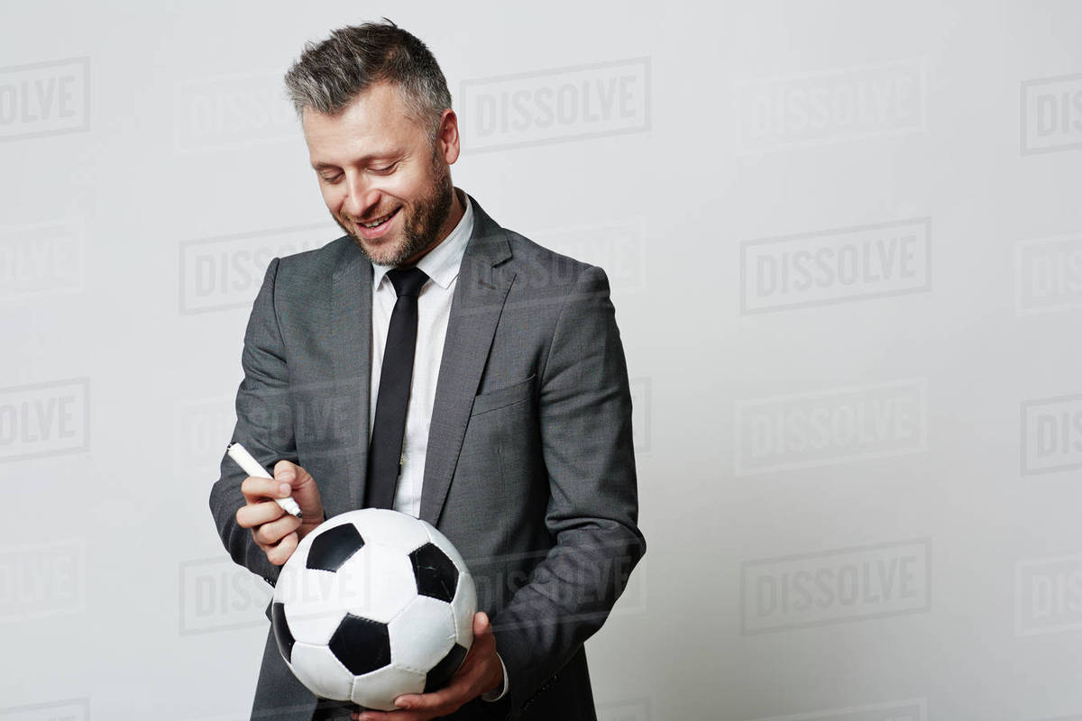 Successful man signing soccer ball - Stock Photo - Dissolve