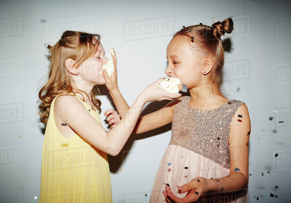 Two little girls giving a piece of cake to each other - Royalty-free ...