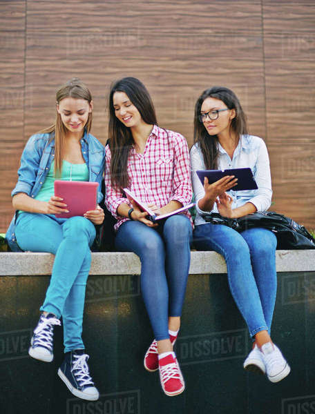 Three college students sitting together and using tablet pc - Stock ...