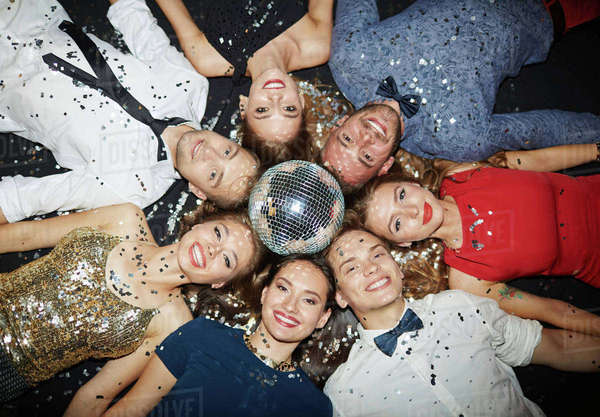 Circle of friends lying on the floor of night club around disco ball ...