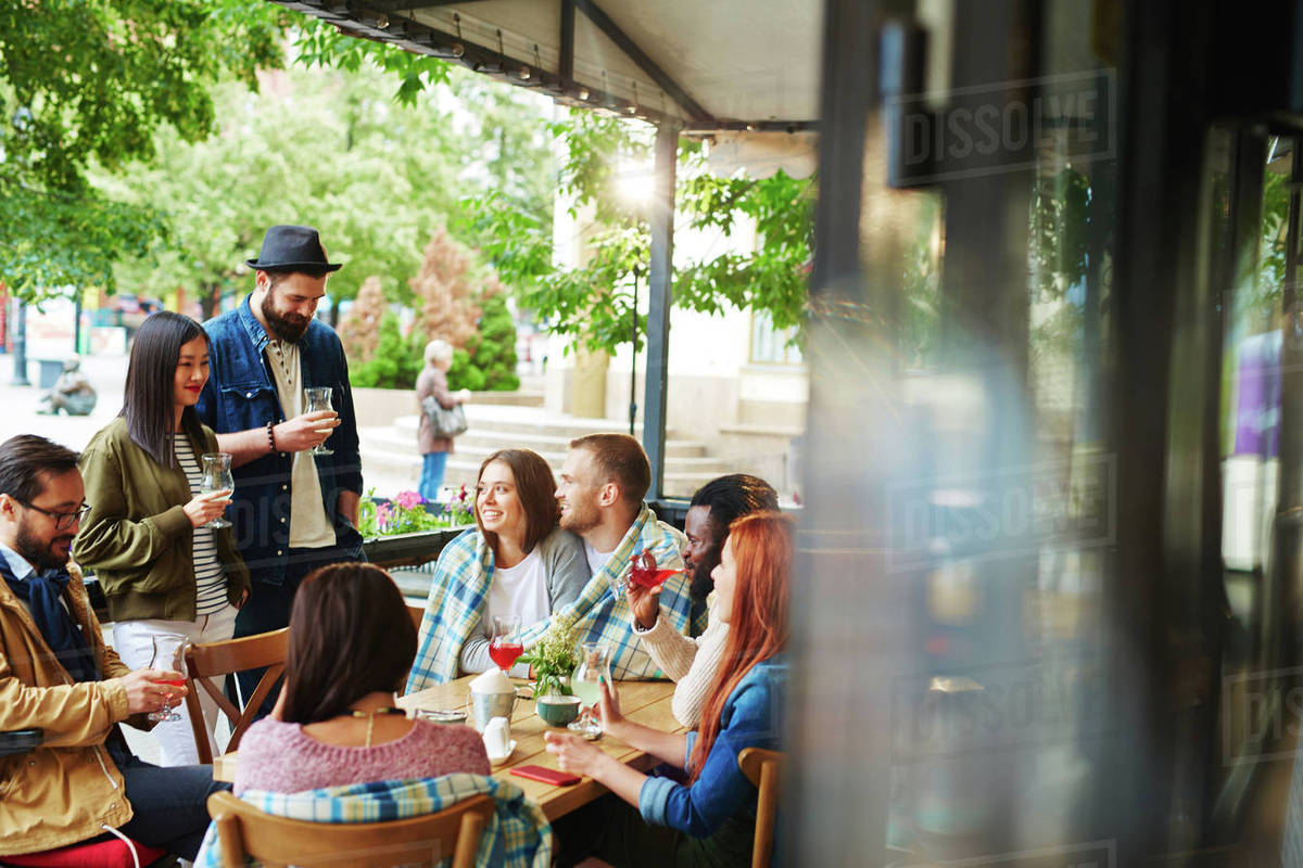 Group of young friendly people talking in outdoor cafe - Royalty-free ...