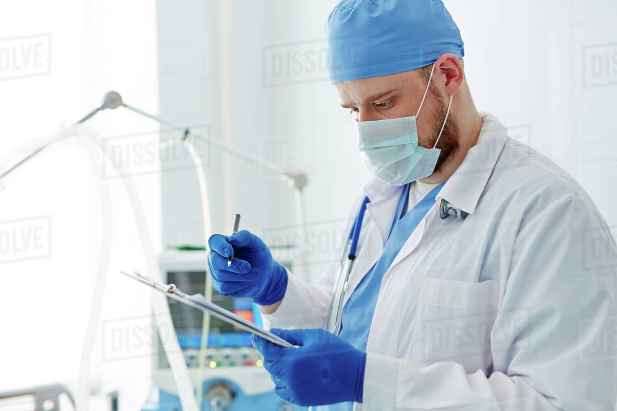 Young doctor making notes in medical document - Royalty-free Stock ...