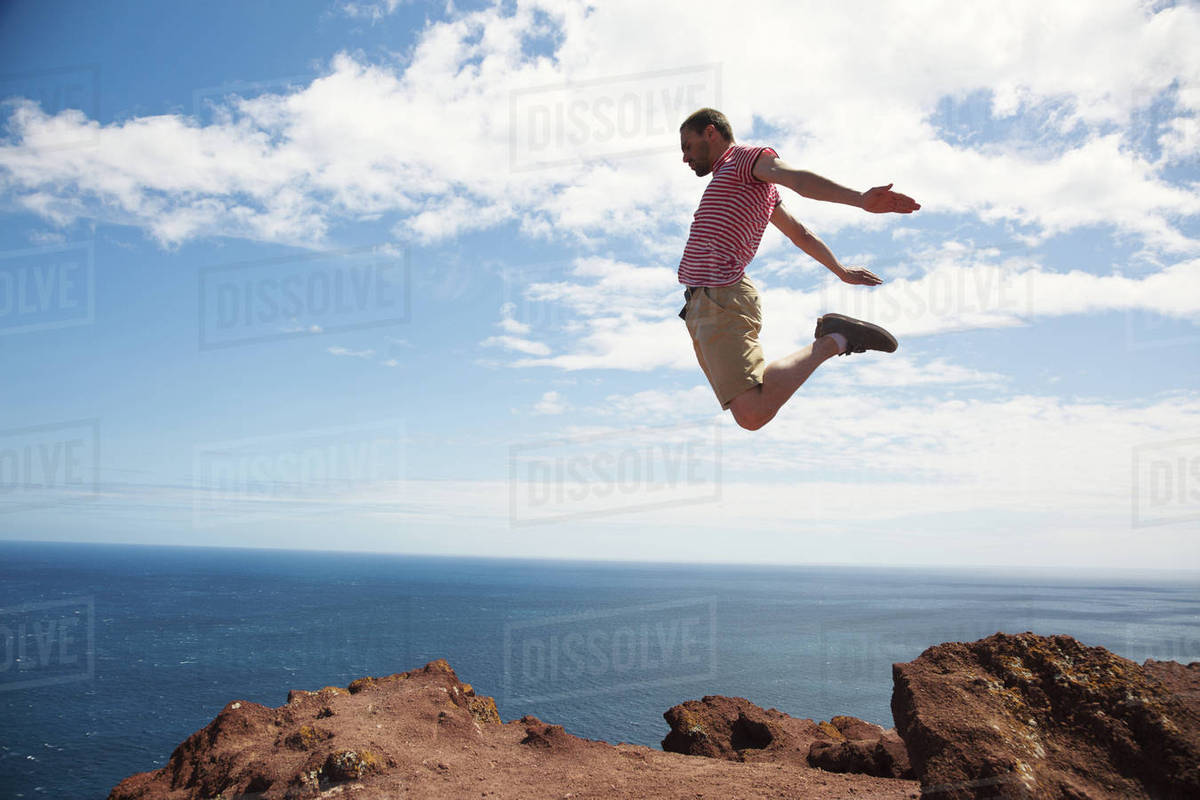 Energetic guy jumping over cliff by seaside - Royalty-free Stock Photo ...