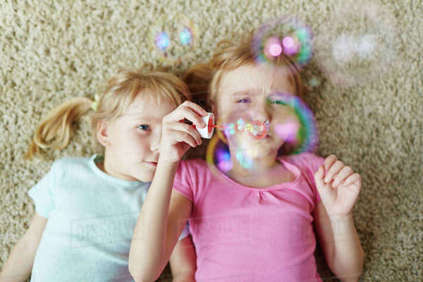 Little girls blowing bubbles at home - Royalty-free Stock Photo | Dissolve