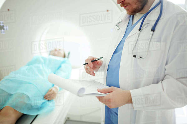 Doctor checking medical record of his patient during CT scan - Royalty ...
