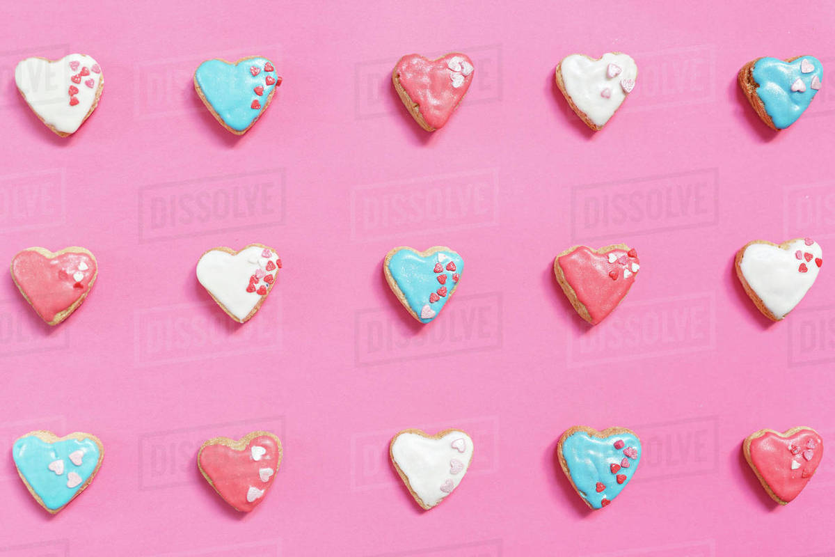 Pink background with rows of homemade heart-shaped pastries - Stock ...
