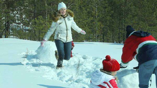 Family making a snowman together, mom and daughters helping father to ...