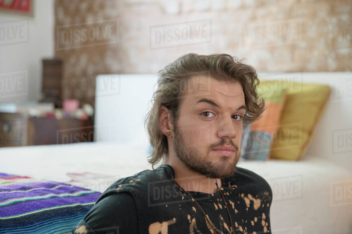 Young man sitting beside his bed - Royalty-free Stock Photo | Dissolve