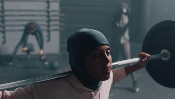 Muslim woman athlete training using barbell weightlifting exercise ...