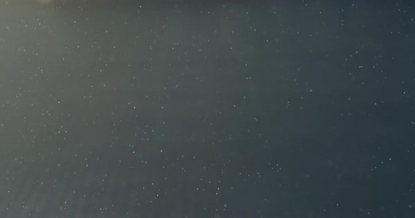 Chalk powder dust particles floating in dark gym falling slow motion ...