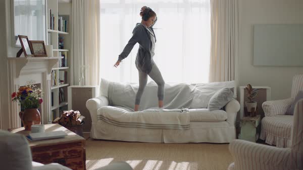 Happy young woman dancing at home having fun listening to music wearing ...