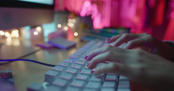 Teenage girl hands typing on keyboard with colorful backlight gamer ...