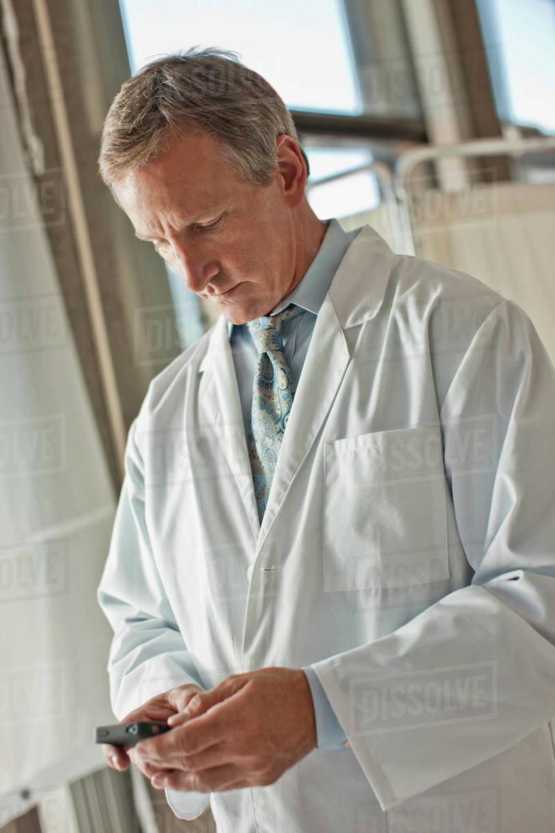 Doctor checking his mobile phone. - Royalty-free Stock Photo | Dissolve