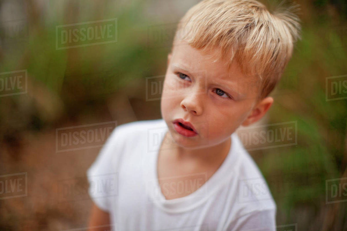 Young boy standing in a garden looking confused, - Stock Photo - Dissolve