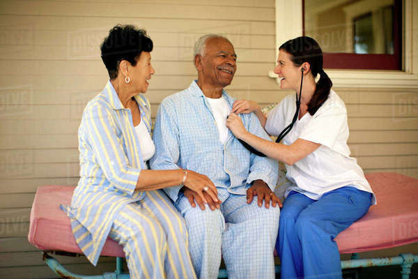 Nurse sitting on the deck of rest-home with elderly patients and ...