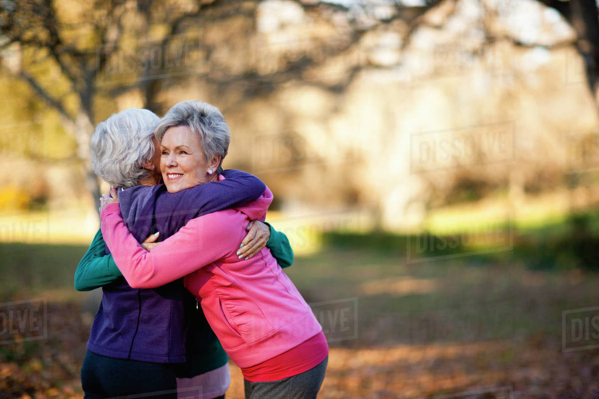 Three senior women hugging each other in a park. - Stock Photo - Dissolve