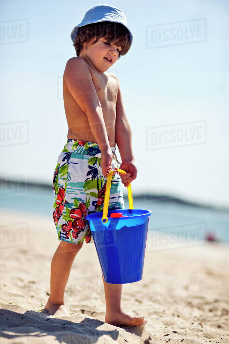 Young boy with bucket of sand. - Royalty-free Stock Photo | Dissolve