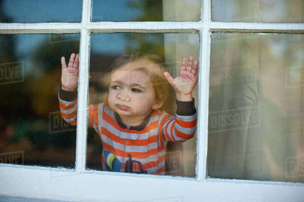 Baby girl pressing her face against a window plane. - Stock Photo ...
