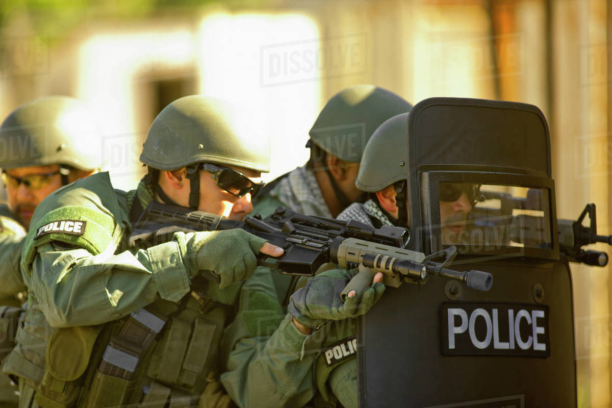 Four police officers holding weapons and protection about to enter a ...