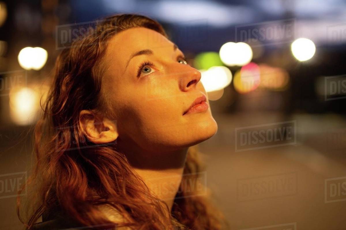Close-up shot of a young woman looking up while standing outdoors at ...