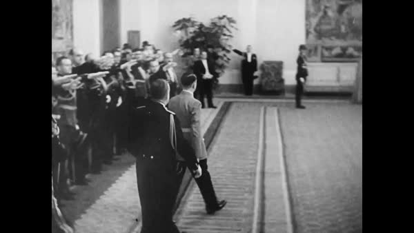 World War Two. Adolf Hitler walk into a room. A delegation greets him ...
