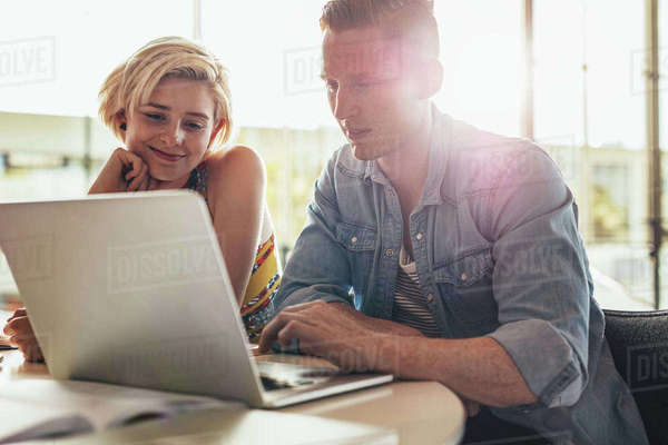 Two young students using laptop in class. University students working ...