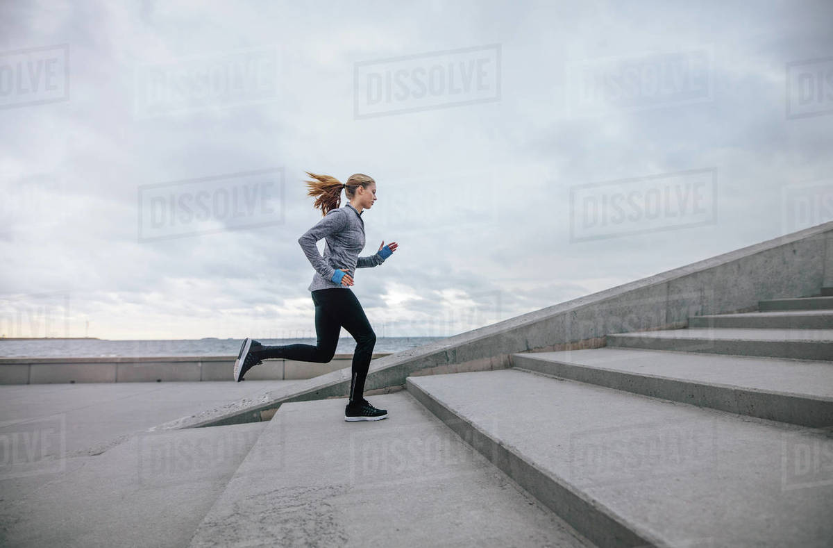Side view shot of fitness woman running up on steps. Female runner ...