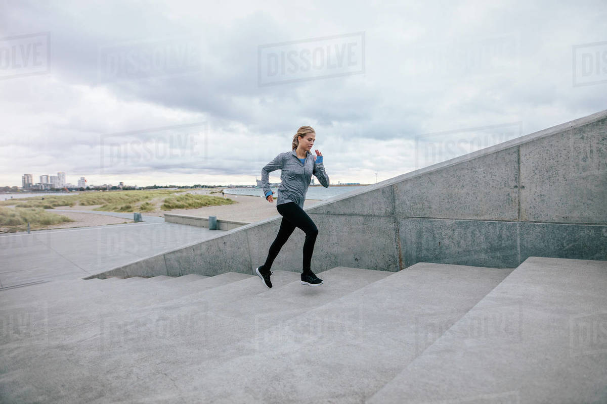 Full length shot of fit young woman running up the steps. Fitness ...