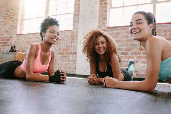 Portrait of three young women in fitness class looking at camera and ...