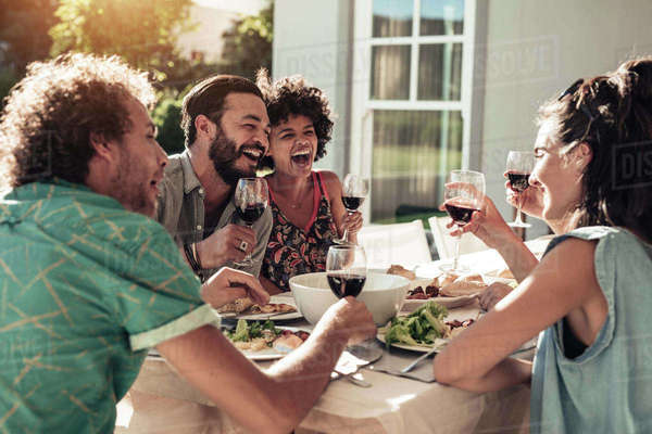 Multiracial young people having food and drinks outdoors. Young friends ...