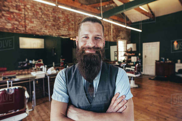 Portrait of happy young barber smiling at his barbershop. caucasian ...