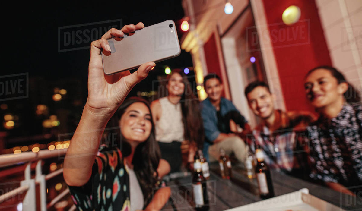 Friends having a party on the rooftop making a selfie with smart phone ...