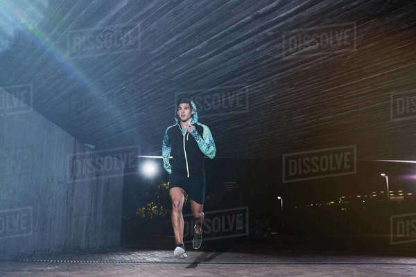Full length shot of a young man jogging at night. Fit male athlete ...