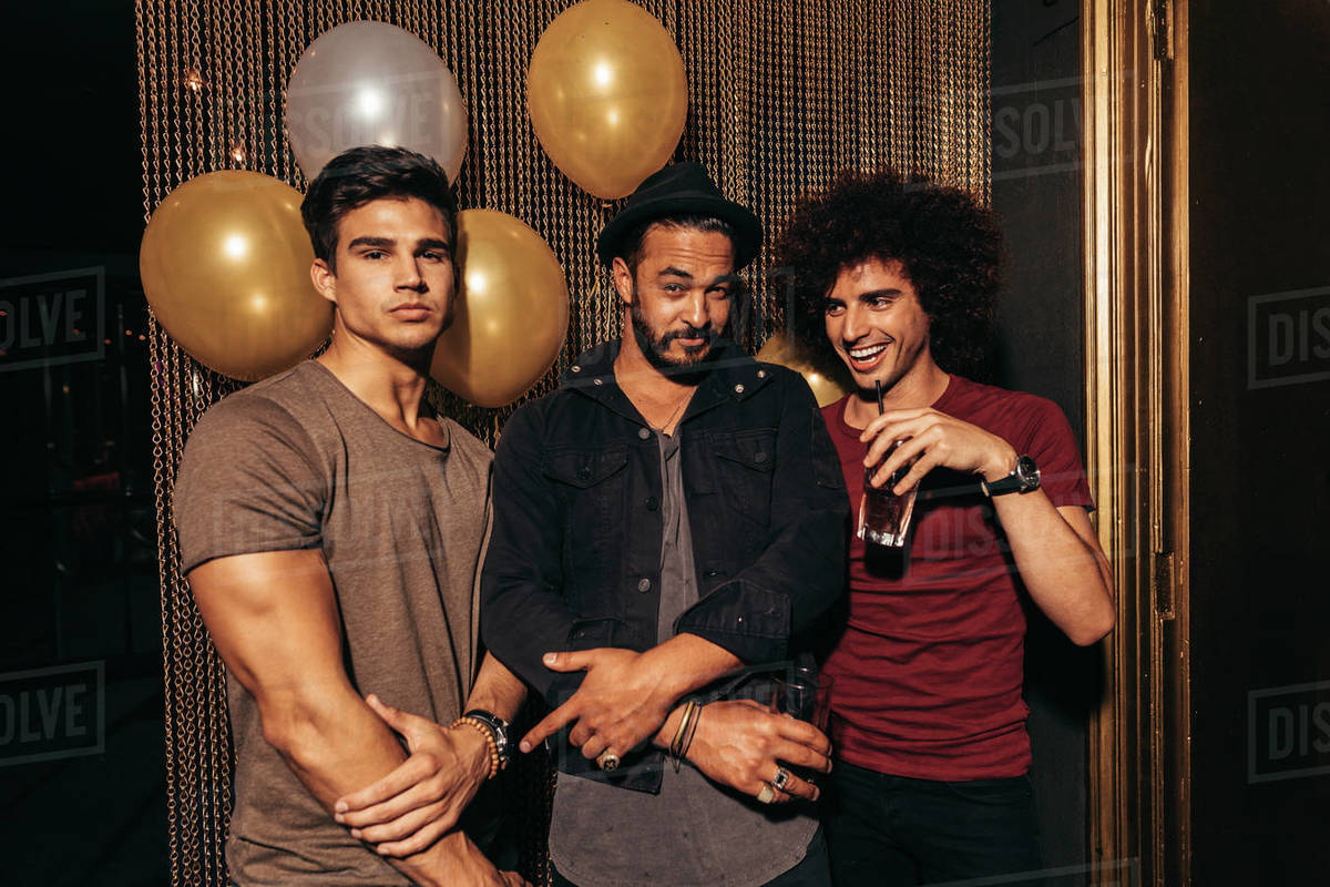 Portrait of three young men partying at the nightclub. Group of men ...