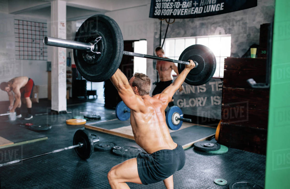 Muscular man Lifting weights at crossfit gym. Fitness male during cross ...