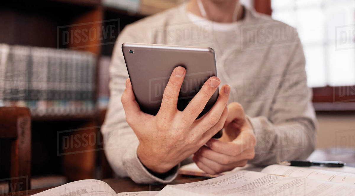 Close up of college student using tablet pc in library. Young student ...