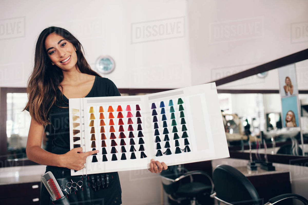 Professional woman hairdresser pointing at the hair color sample chart ...