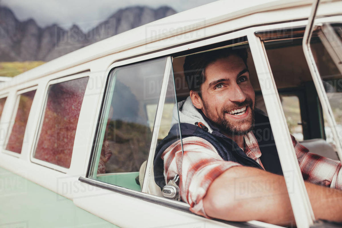 Smiling man on roadtrip driving a van and looking away. Caucasian male ...