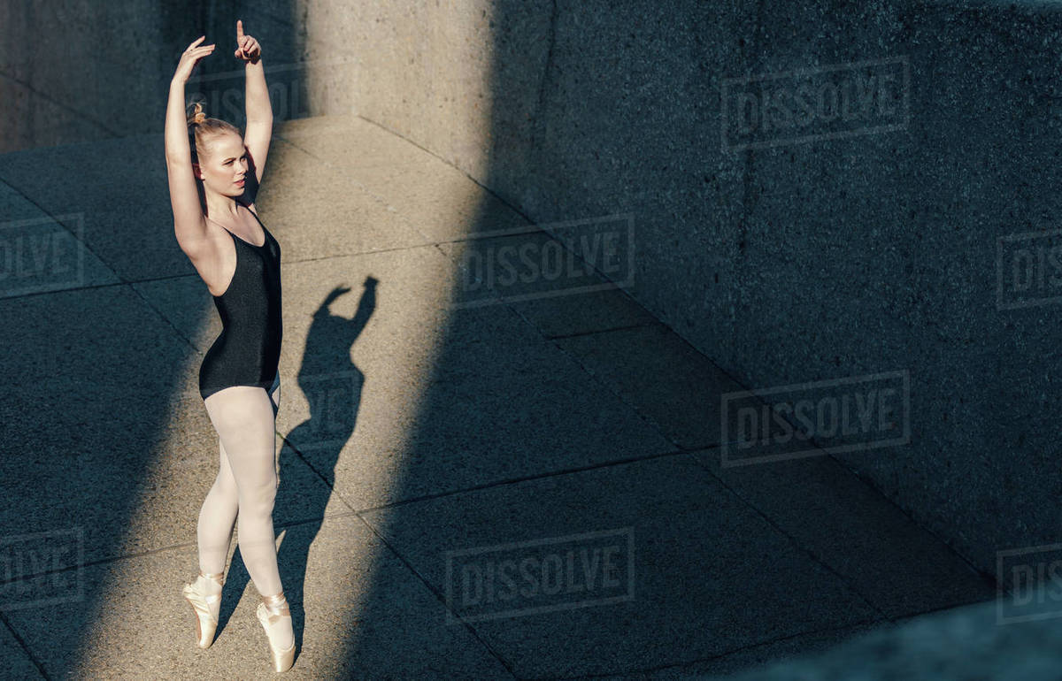 Ballet dancer practicing dance moves outdoors. Dancer standing tall on ...