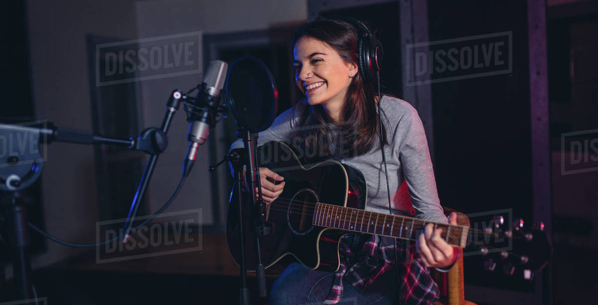 Female singer playing guitar and singing a song. Woman performing in a ...