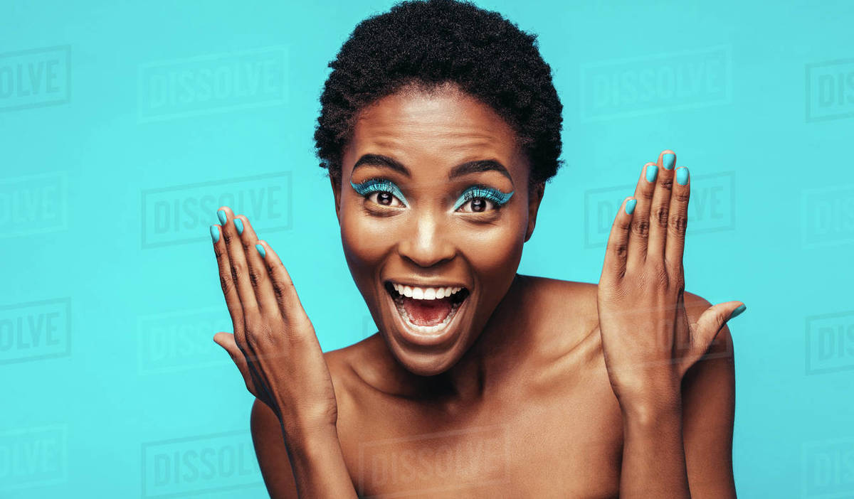 Close up of woman with blue eye shadow and nail paint against blue ...