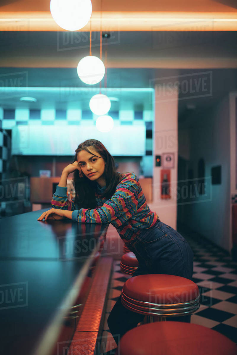 Beautiful young woman standing by bar counter. Female in 90s style ...