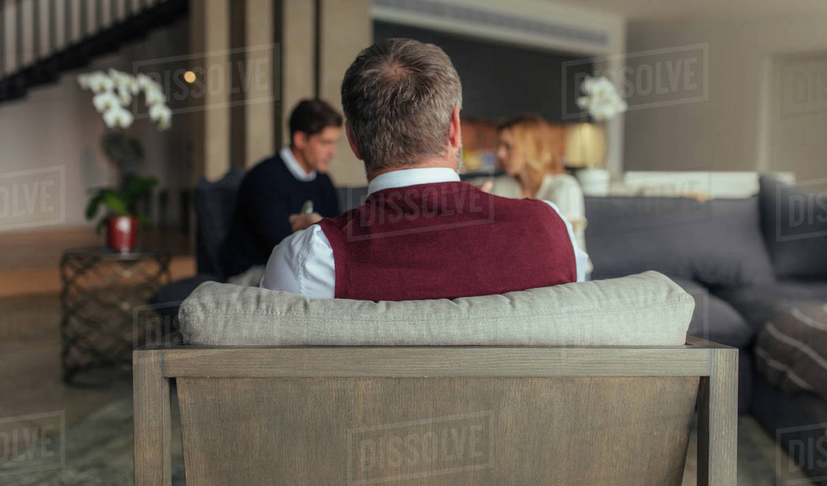 Rear view of psychologist sitting on chair with couple talking in ...