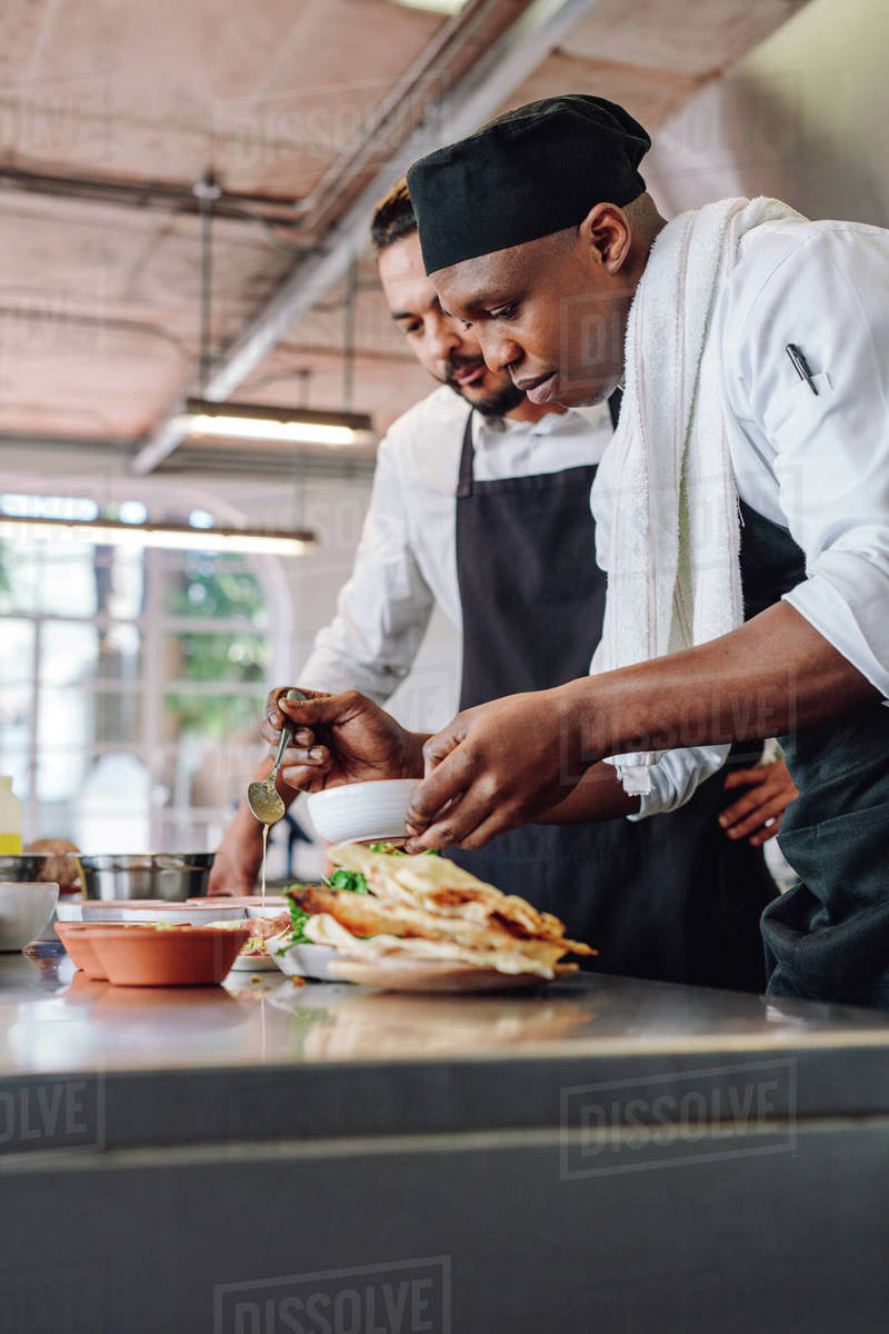 Two professional cooks working at restaurant kitchen together. Chefs ...
